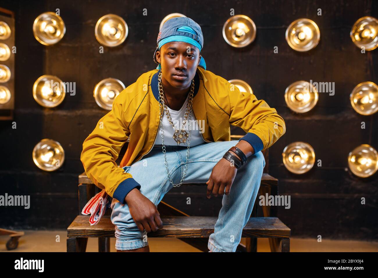 Black rapper in cap sitting on the steps, singer on stage with ...