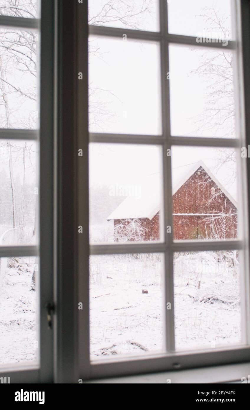 Typical red barn in the winter, view through the window, rural scene in ...