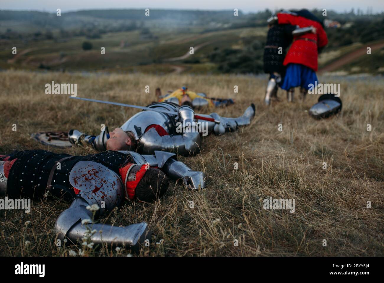 Wounded medieval knights in armor looks at the dead after great battle ...