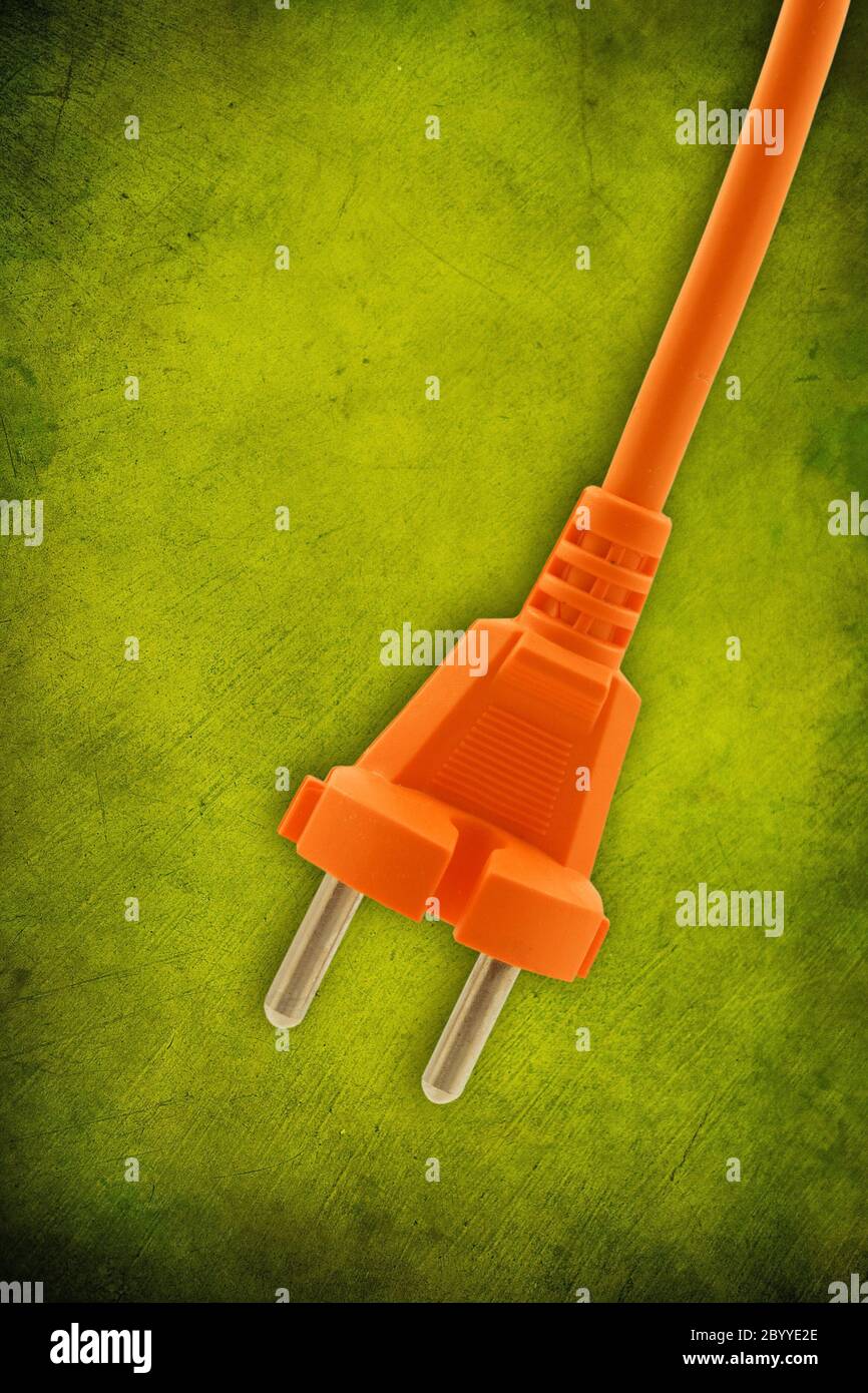 orange electrical plug on green background Stock Photo - Alamy