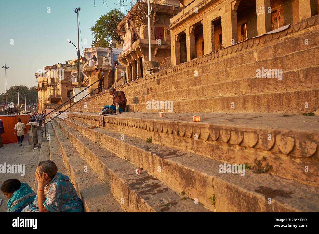 Devotees and travelers sit on the steps of Riva Ghat, facing the rising ...