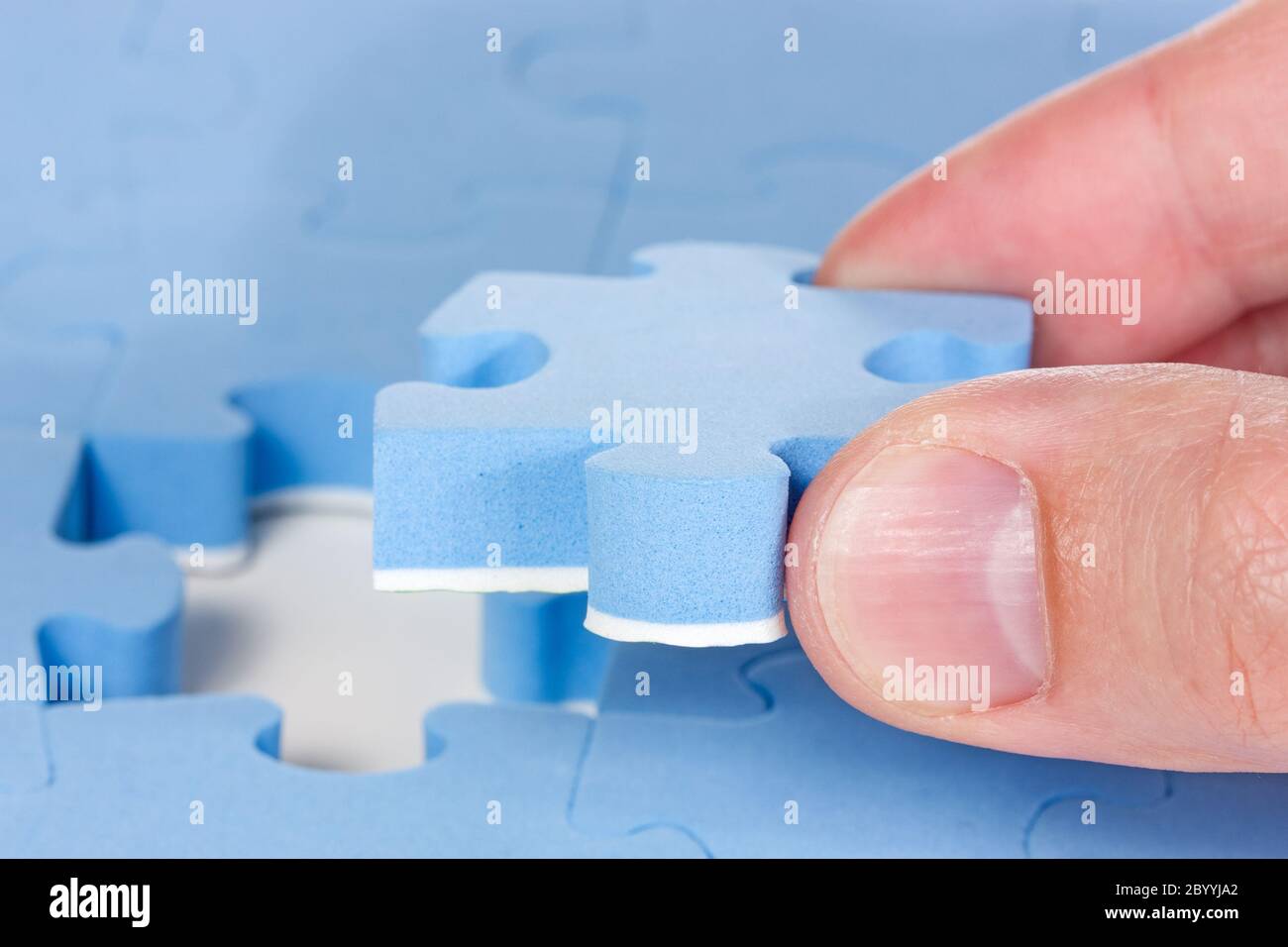 Hand fitting the last puzzle piece Stock Photo - Alamy