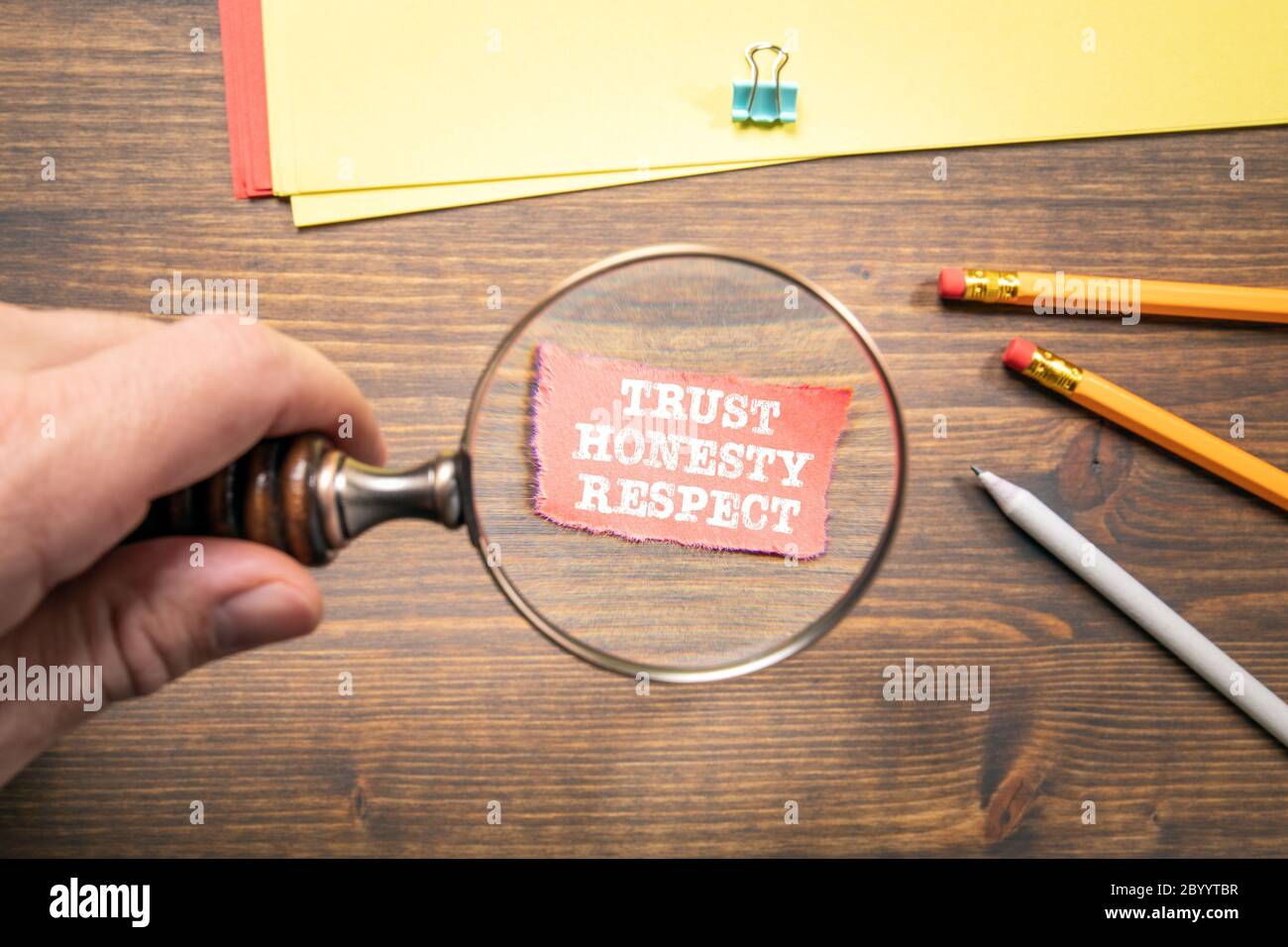 TRUST, HONESTY, RESPECT concept. Man's hand, holding magnifying glass ...