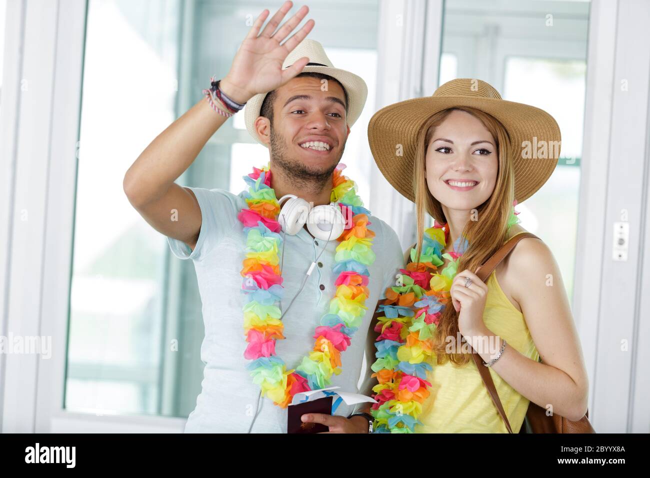 young man and woman waving at people Stock Photo - Alamy