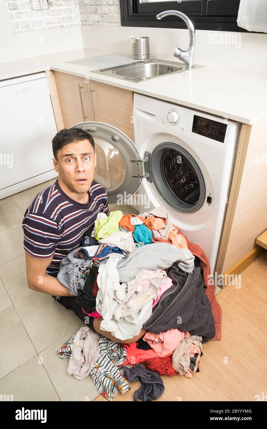 Man in casual clothes worried next to the washing machine, with a lot ...