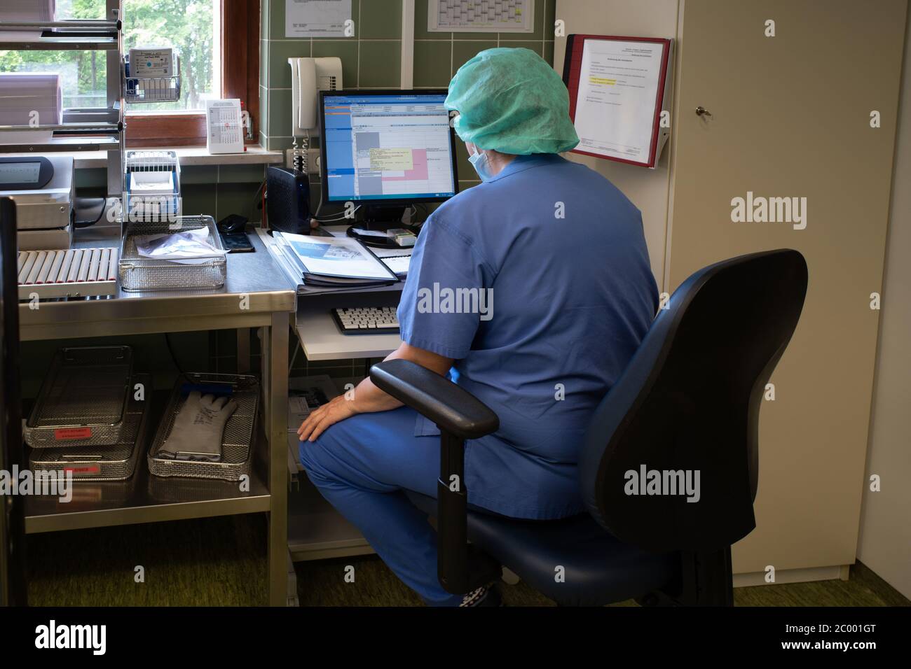 a hospital employee sits at a computer Stock Photo - Alamy