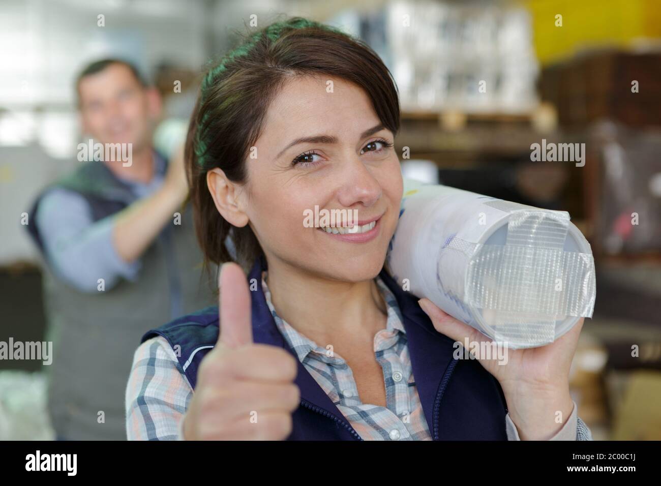 female worker giving a thumb up while carrying material Stock Photo - Alamy