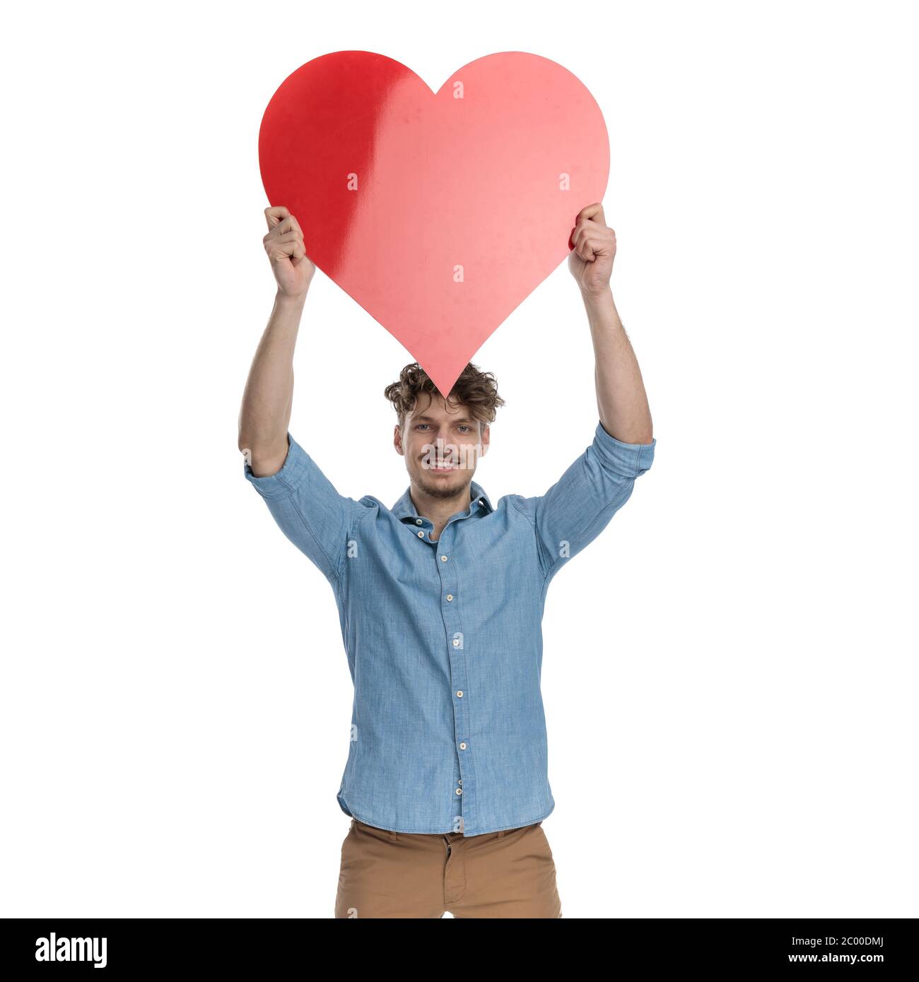 happy young guy holding big red heart above head and smiling, standing ...