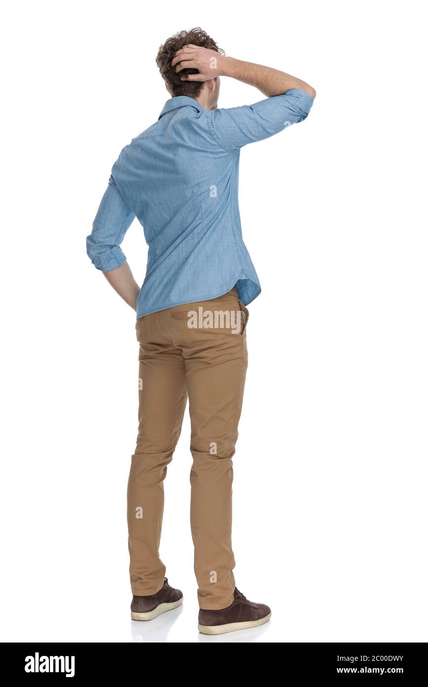 back view of casual guy scratching head, trying to solve difficult ...