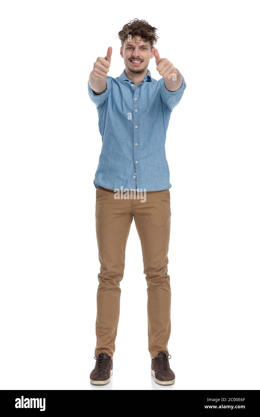 smiling casual guy making thumbs up sign and standing isolated on white ...