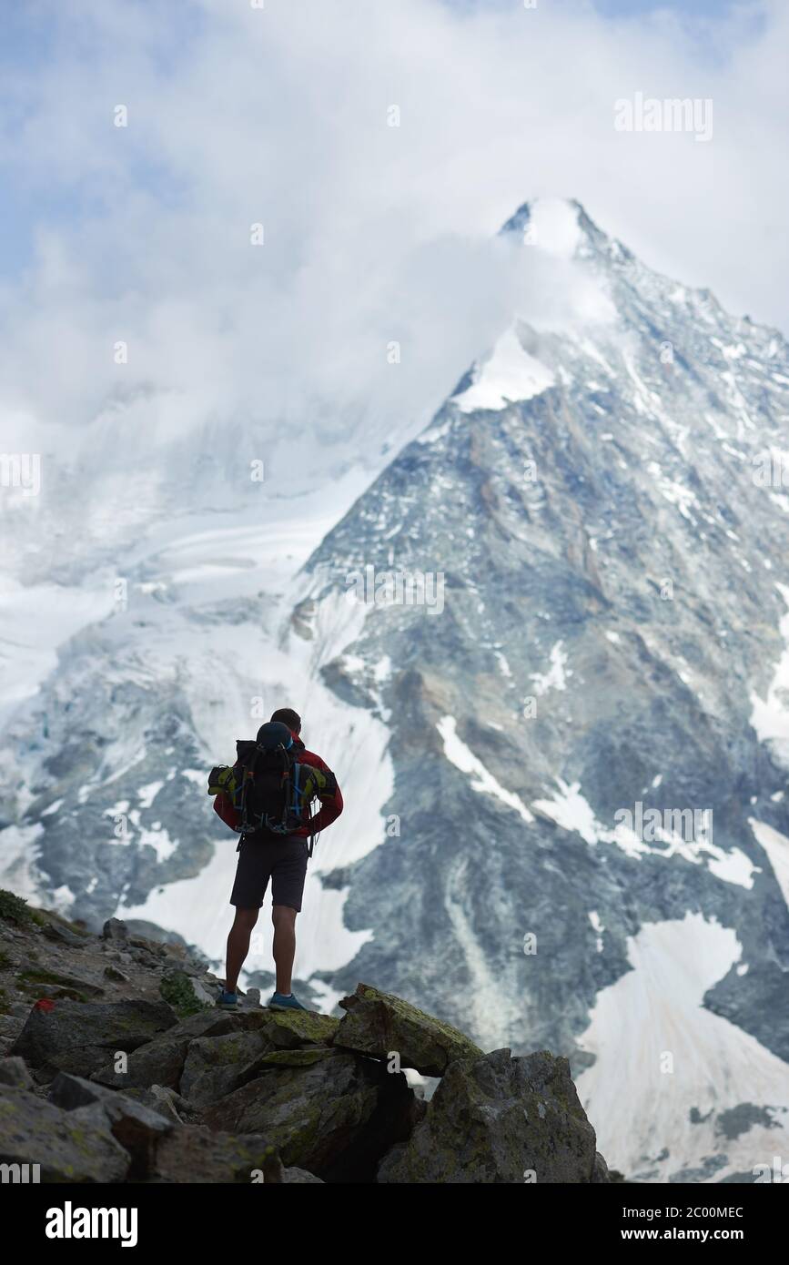 Vertical snapshot of tourist with backpack standing with his back to ...