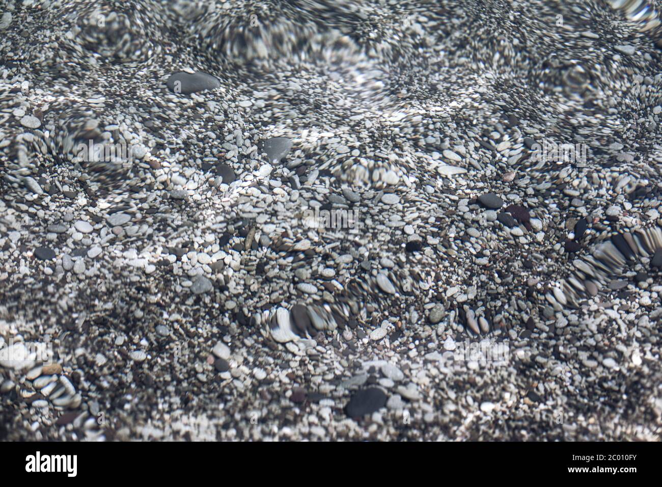 transparent clear calm water surface with small grey pebbles sea bottom ...