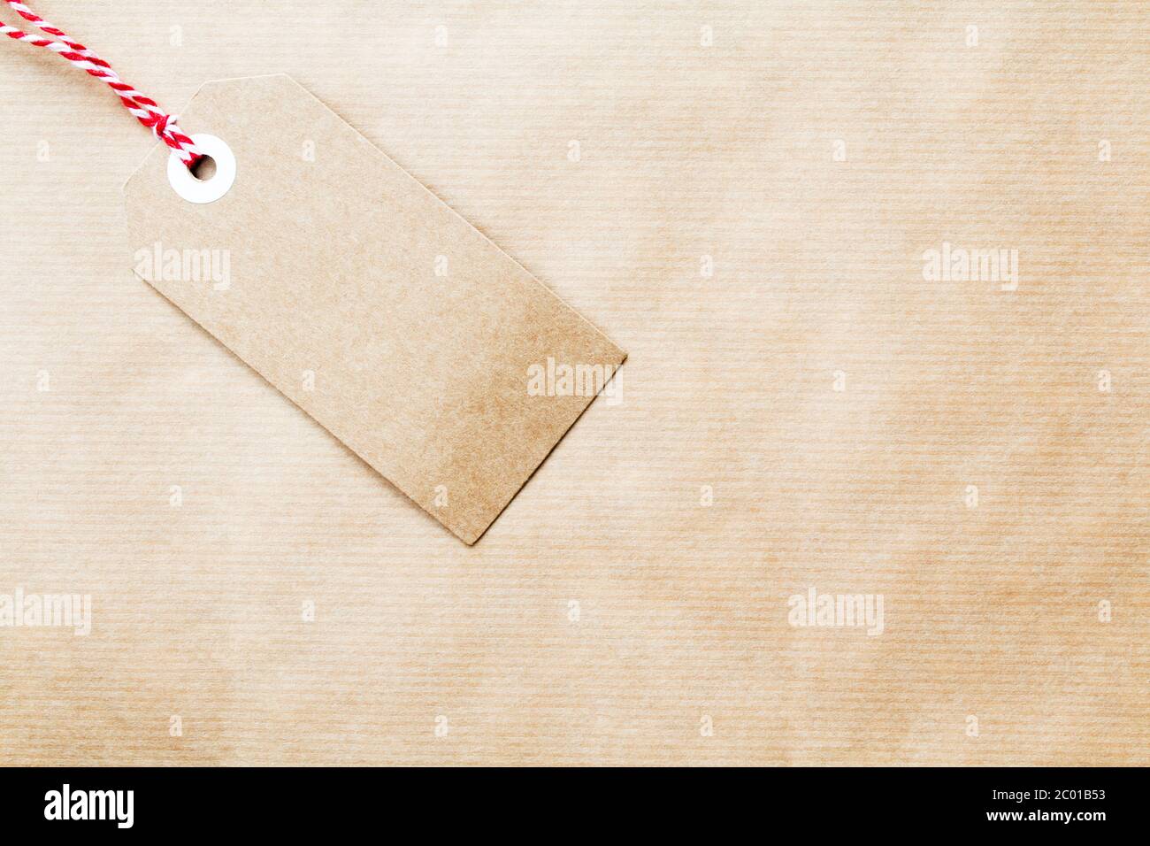 Gift tag made of brown card at an angle on brown paper with red and ...