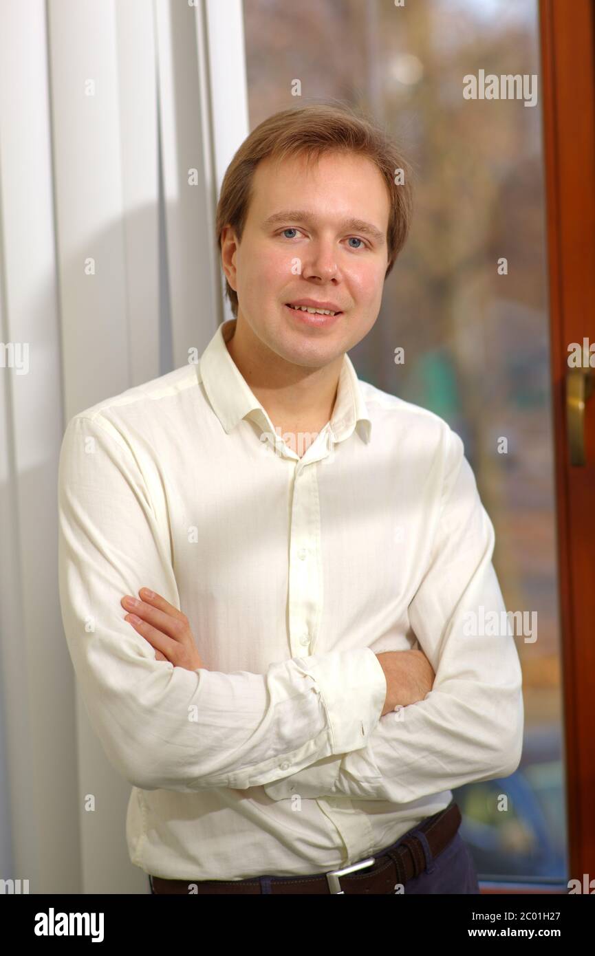 Happy young man standing by the window with blinds Stock Photo - Alamy