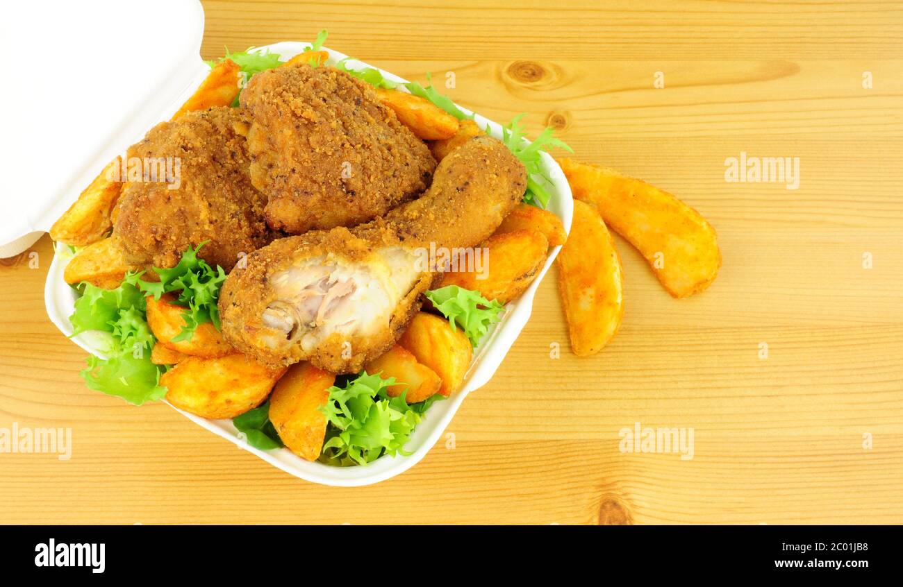 Southern fried chicken portions in a take away box on a wood background ...