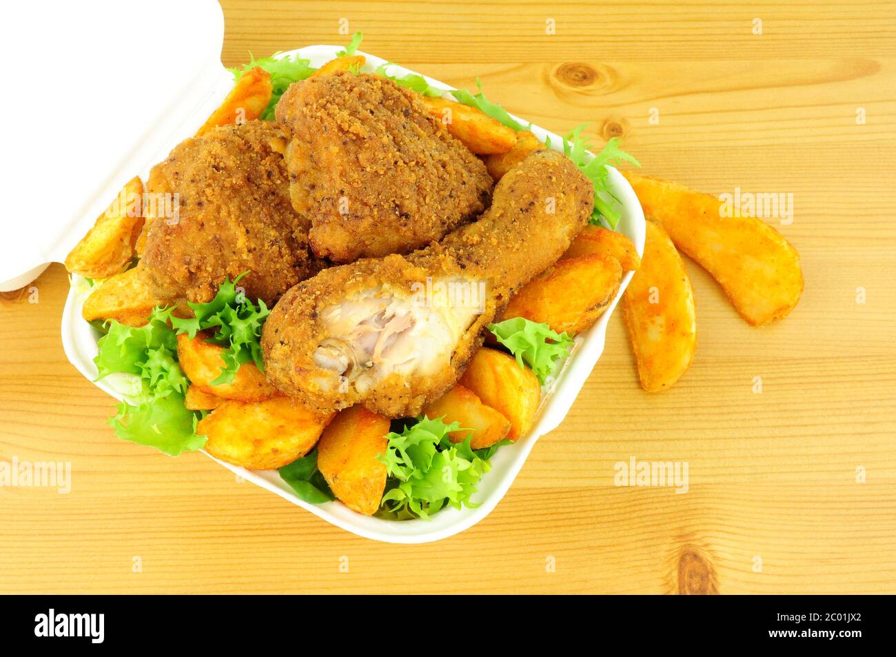 Southern fried chicken portions in a take away box on a wood background ...