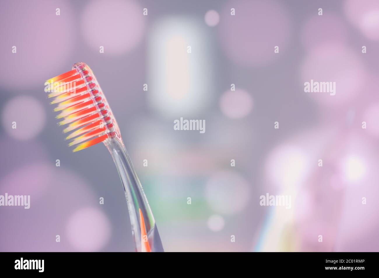 Orange plastic toothbrush on a purple background with round bubbles ...