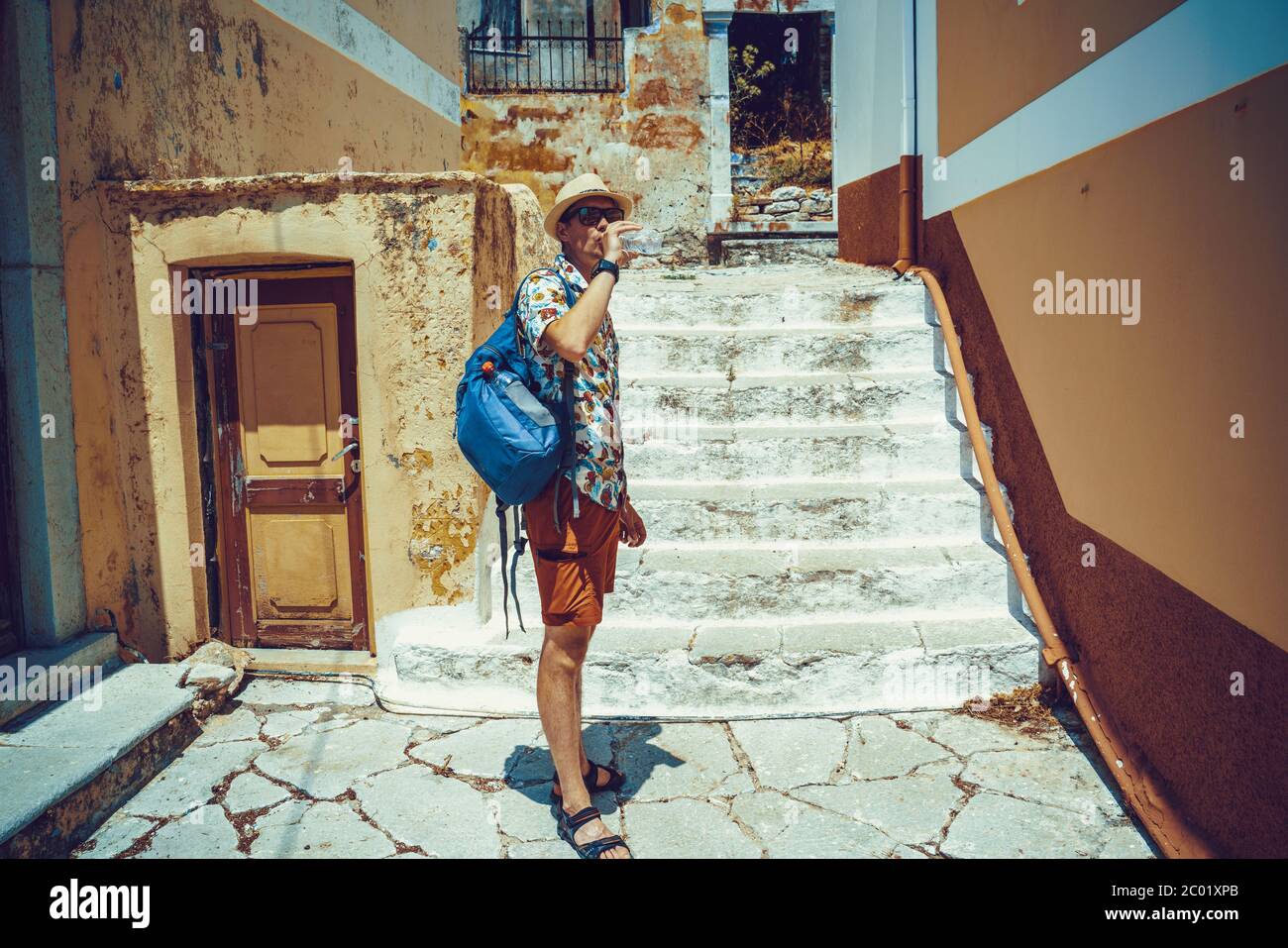 Happy man traveler is drinking water on Greek island of Symi ...