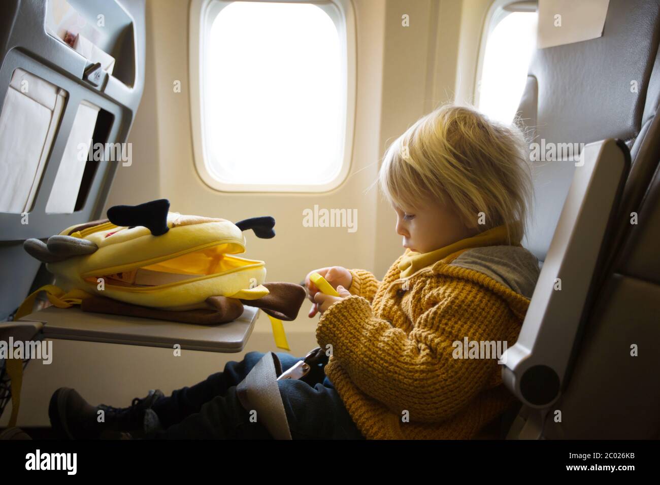 Blonde toddler boy, flying with airplane,enjoying the flight drawing ...