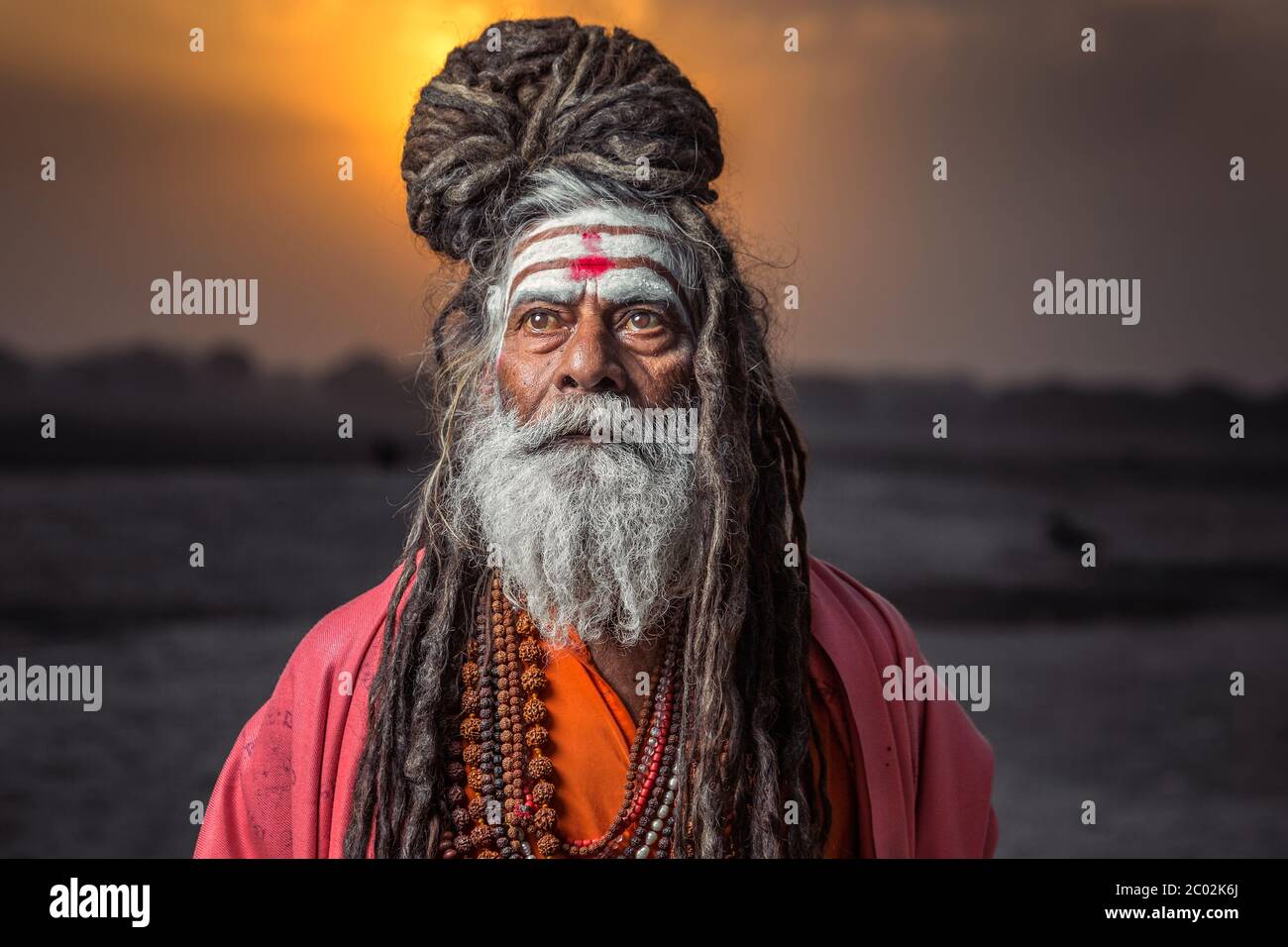 Portrait of sadhu standing with sunrise behind him, Varanasi, India ...