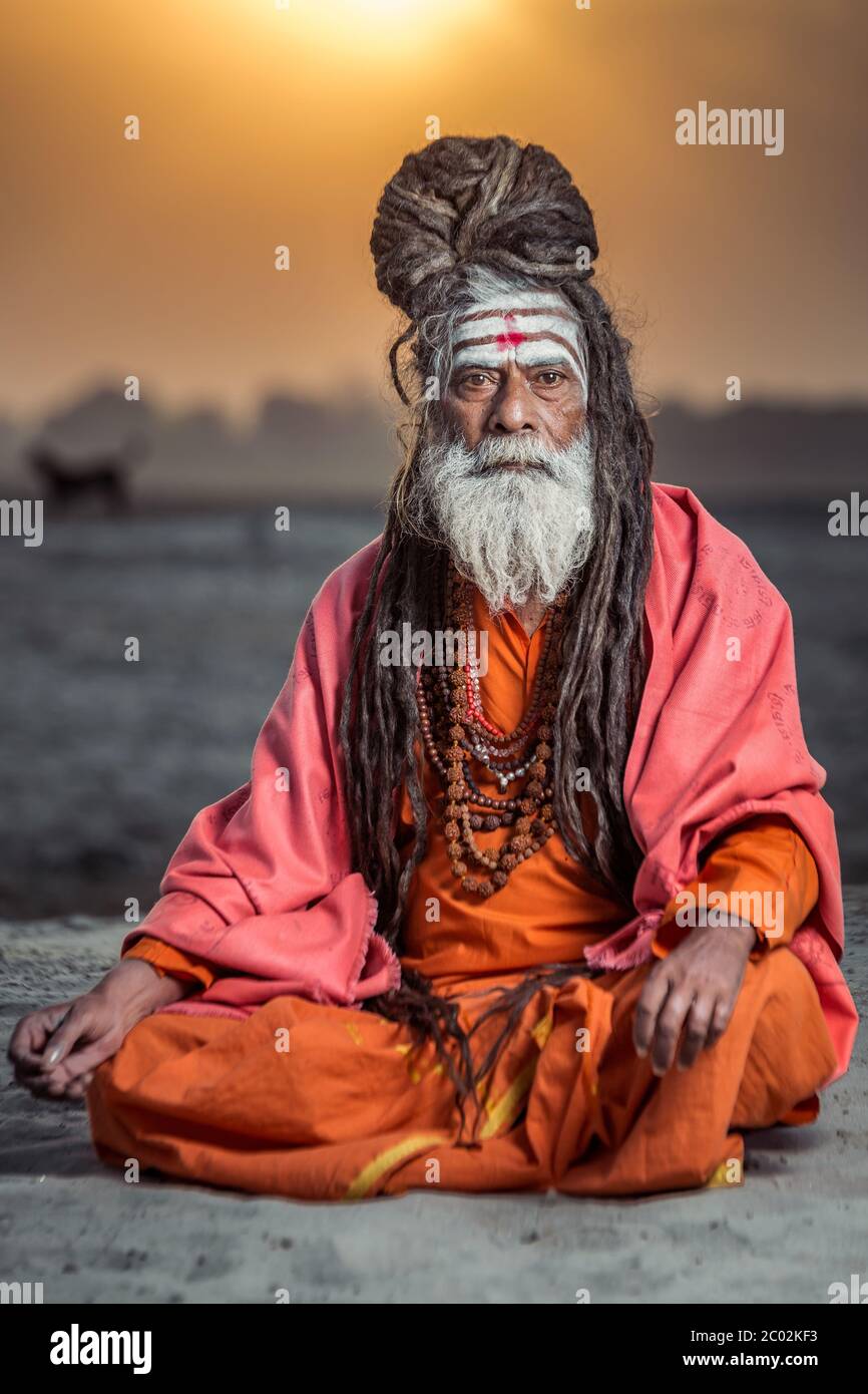 Portrait of sadhu sitting with sunrise behind him, Varanasi, India ...