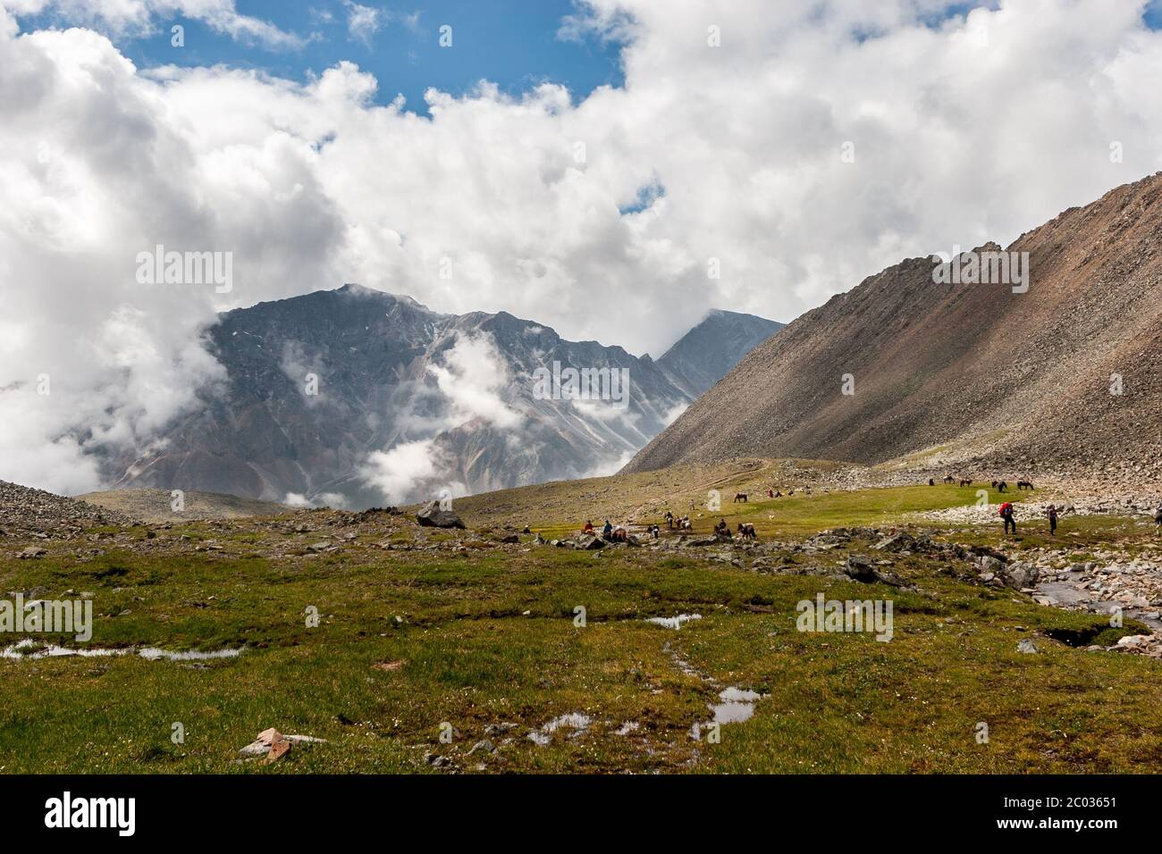 High rocky mountains and people wandering around the valley. Hikers ...