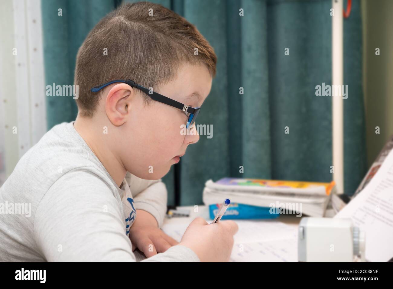 little boy sits at a table and does school lessons Stock Photo - Alamy