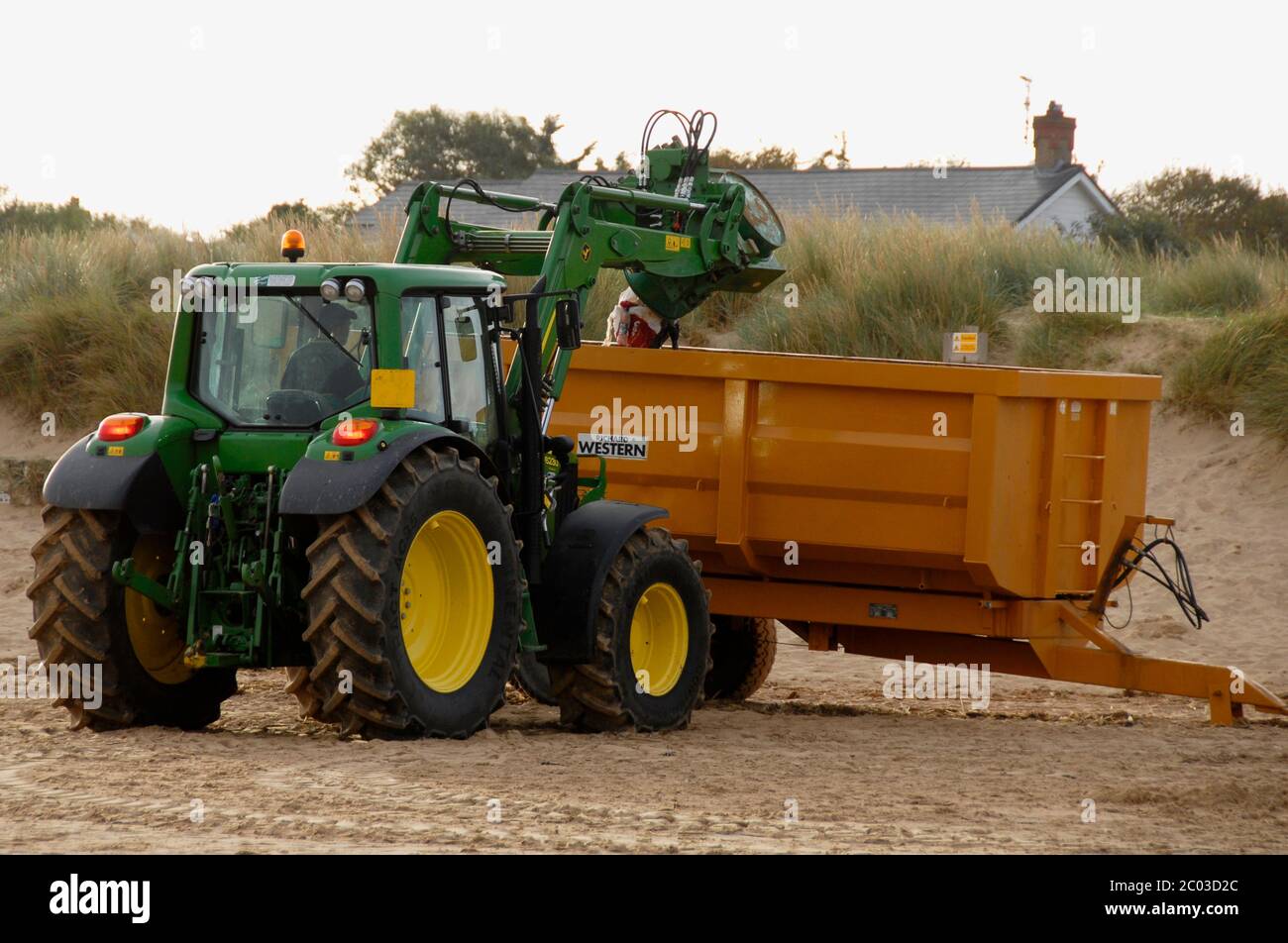 Tractor collecting rubbish bins on beach and emptying them into ...