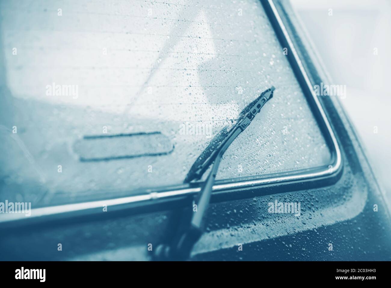 The black windshield wiper on the back window of the car, which is wet ...