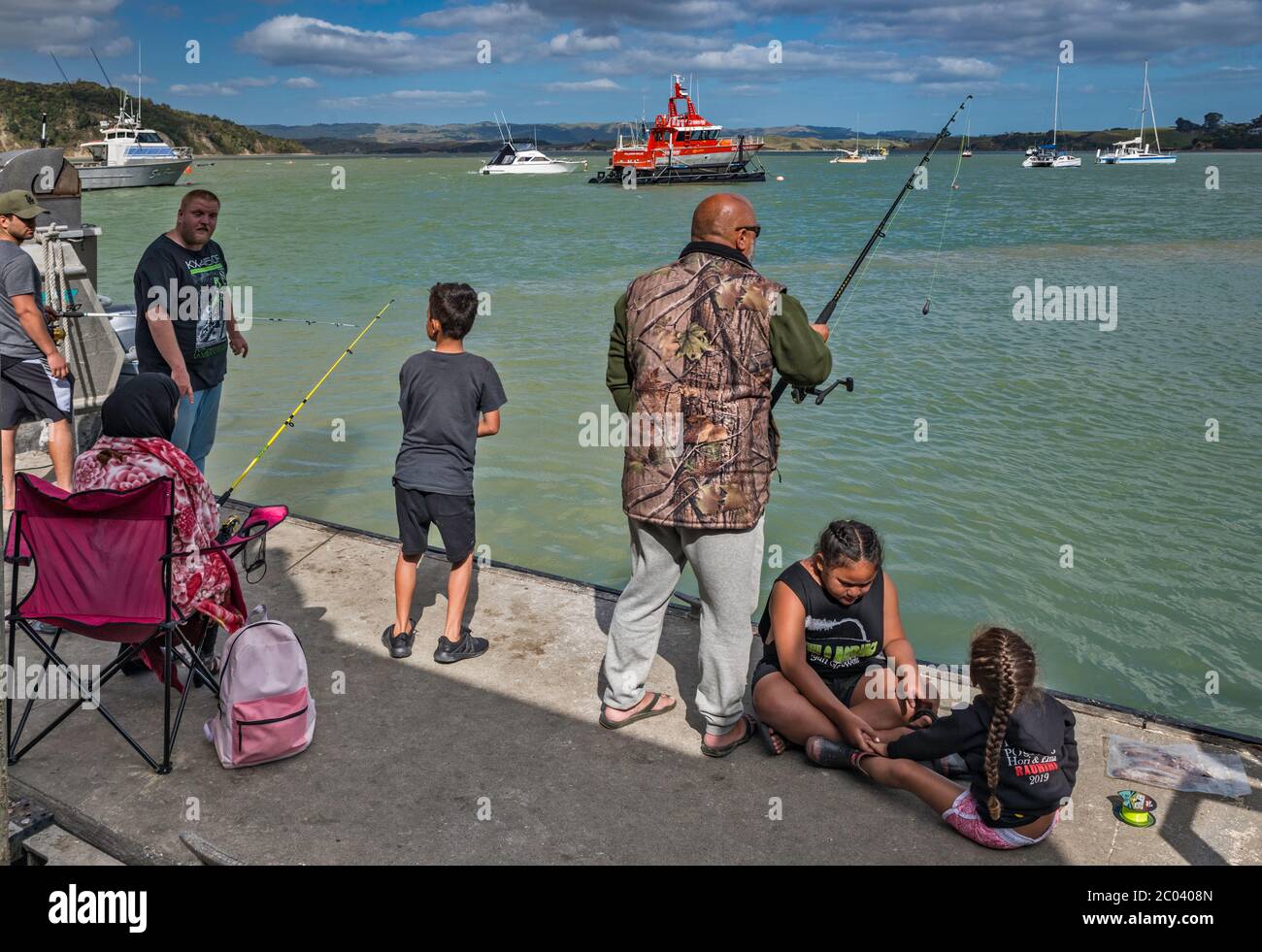People fishing, children playing at Raglan Wharf over Cox Bay in Raglan ...
