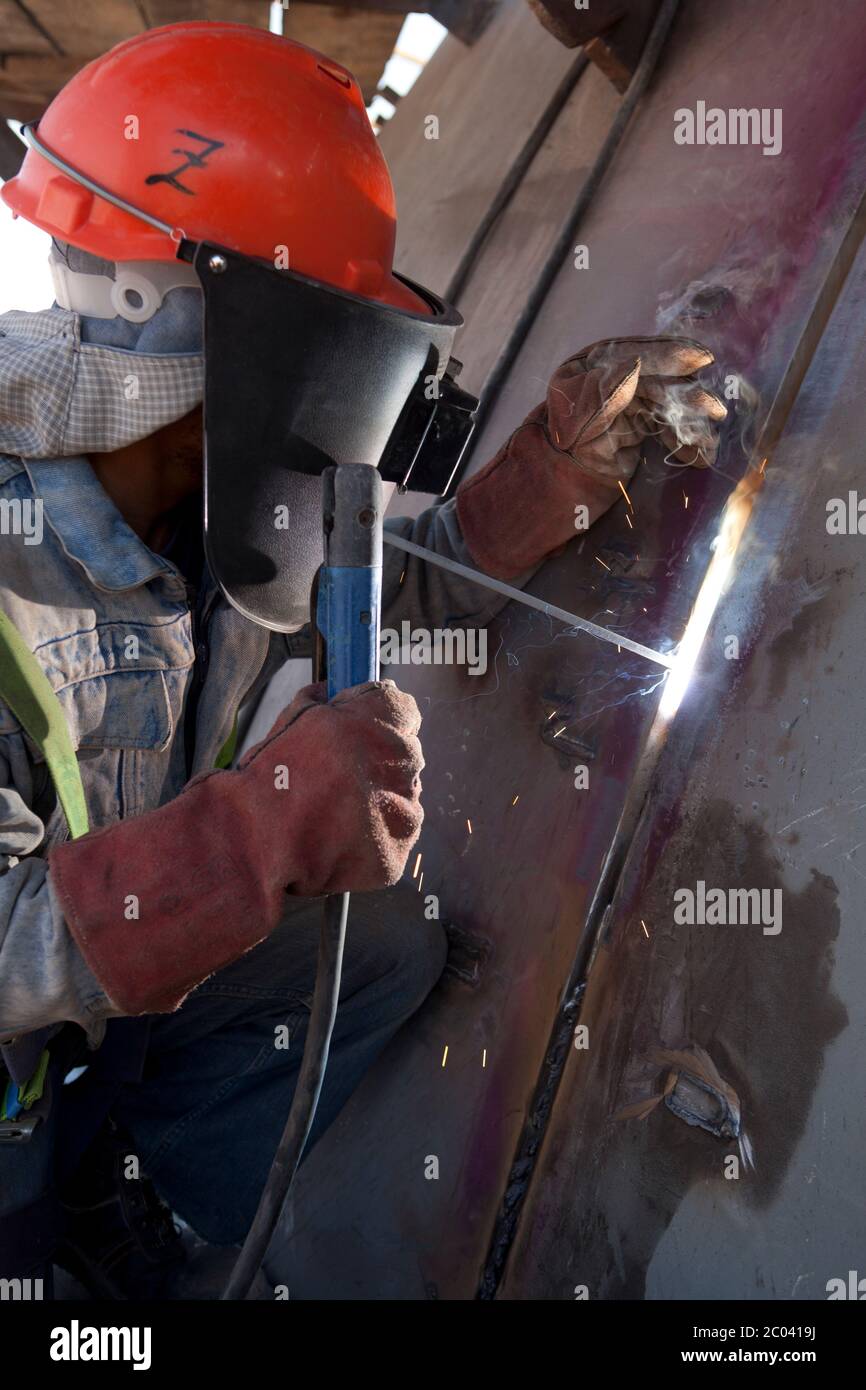 Welders at work completing the construction of an oil tank at a new oil facility in the Sahara ...