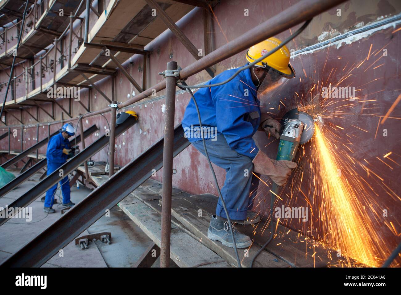 Welder grinding off supports no longer needed during the construction ...