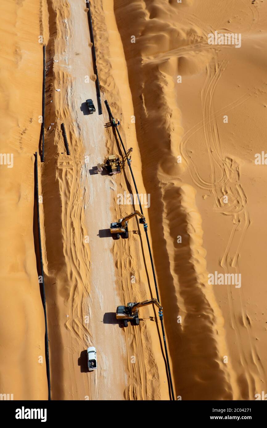 Heavy plant moving a welded pipeline section into a trench in the sand ...