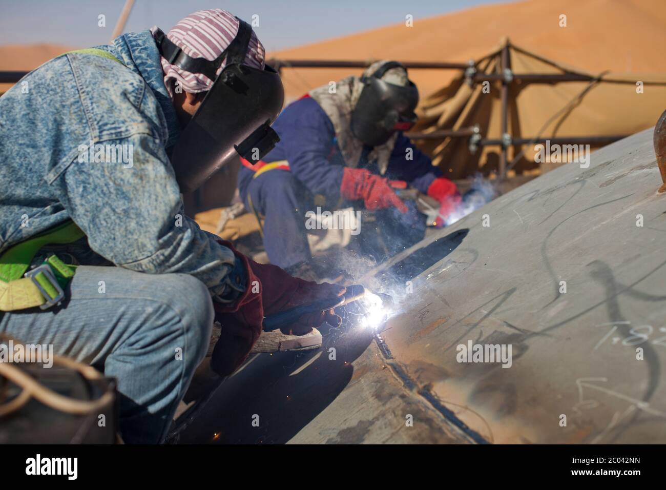 Welders at work completing the construction of a pressure vessel at a new oil facility in the ...