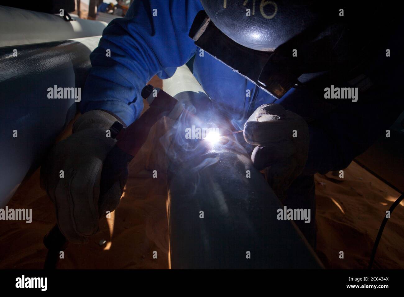 Welders at work completing the construction of an oil tank at a new oil facility in the Sahara ...
