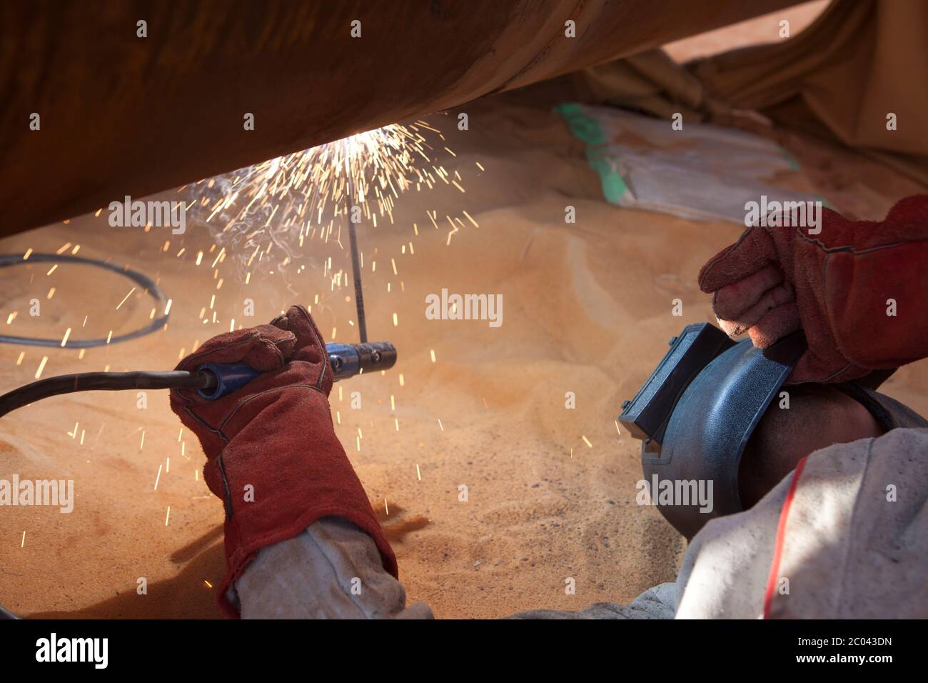 Welders join together an export pipeline in the Sahara desert to carry ...