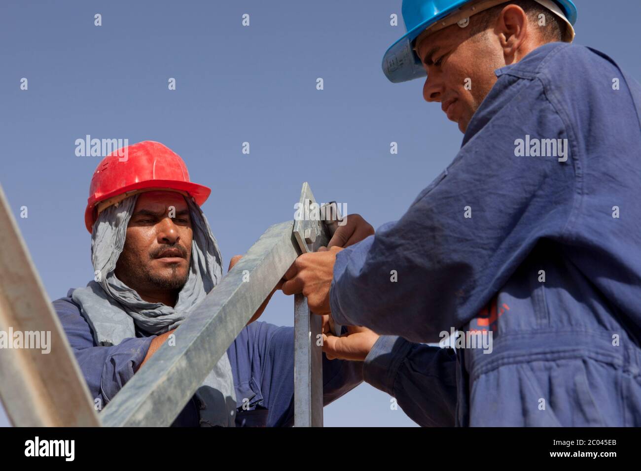 Workers assemble electricity pylons to carry power to a new large oil ...