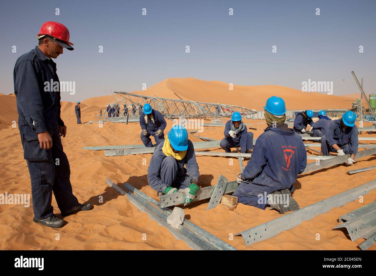 Workers assemble electricity pylons to carry power to a new large oil ...