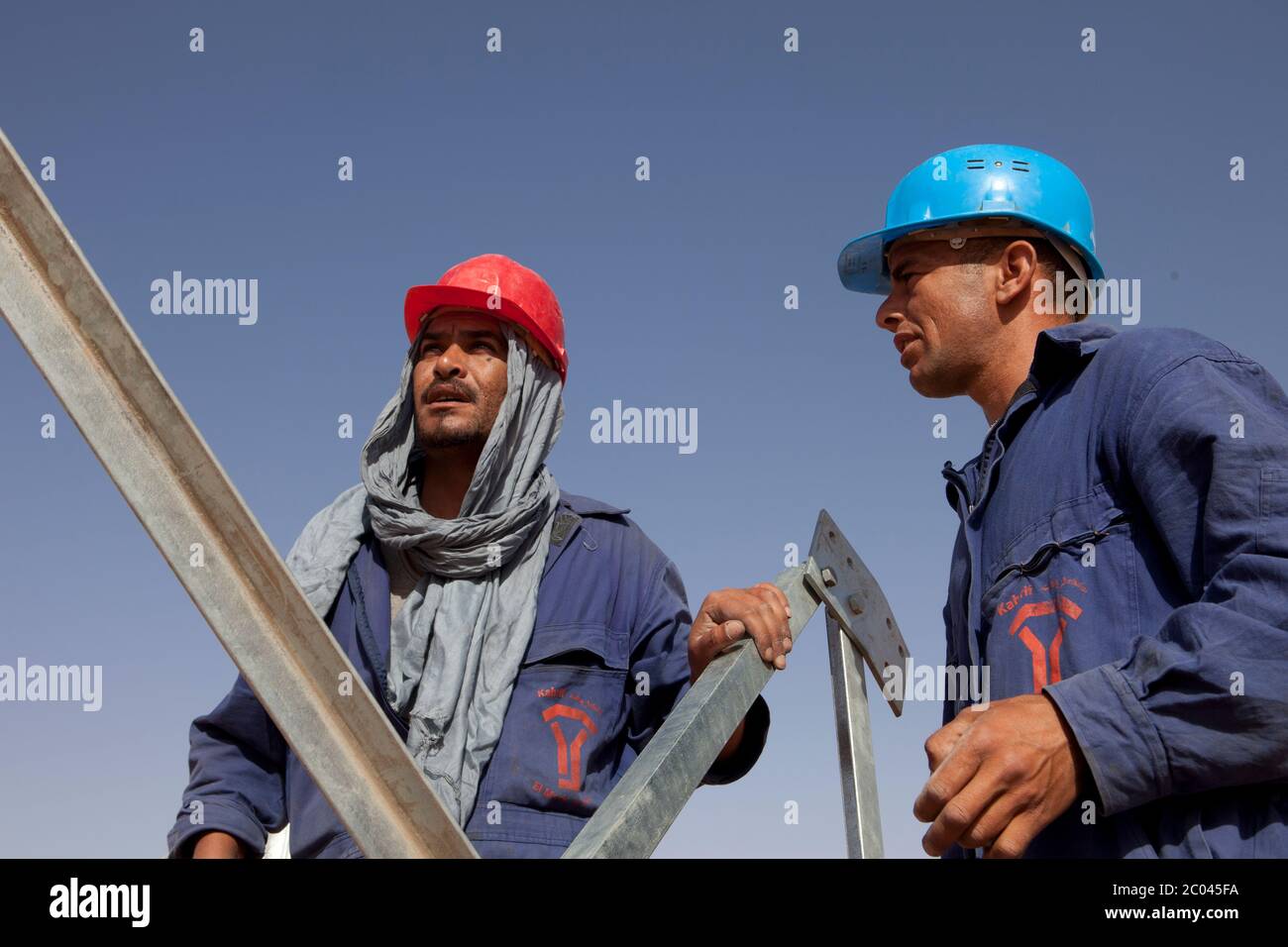 Workers assemble electricity pylons to carry power to a new large oil ...