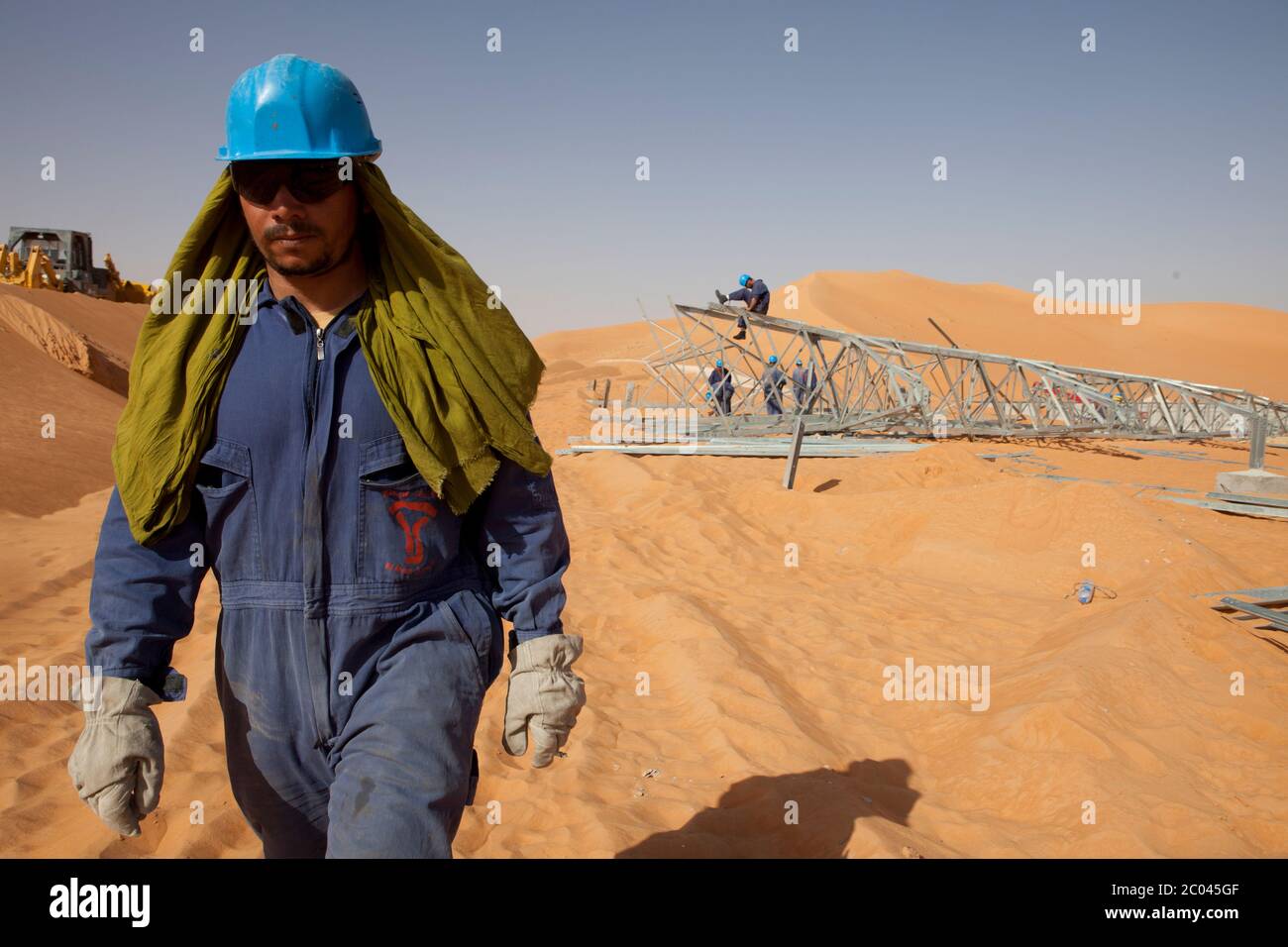 Workers assemble electricity pylons to carry power to a new large oil ...