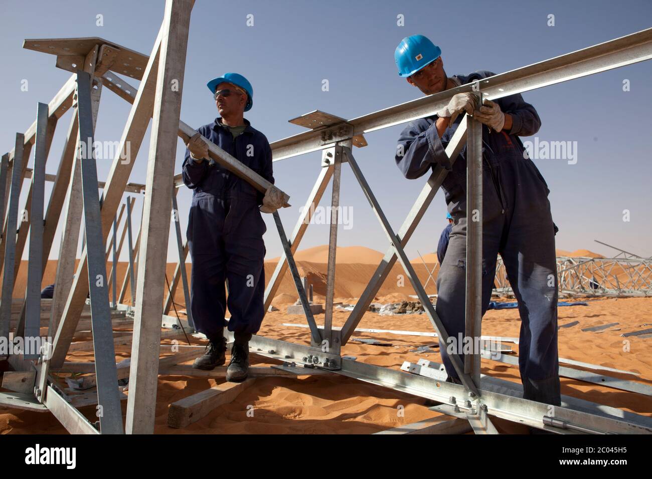 Workers assemble electricity pylons to carry power to a new large oil ...