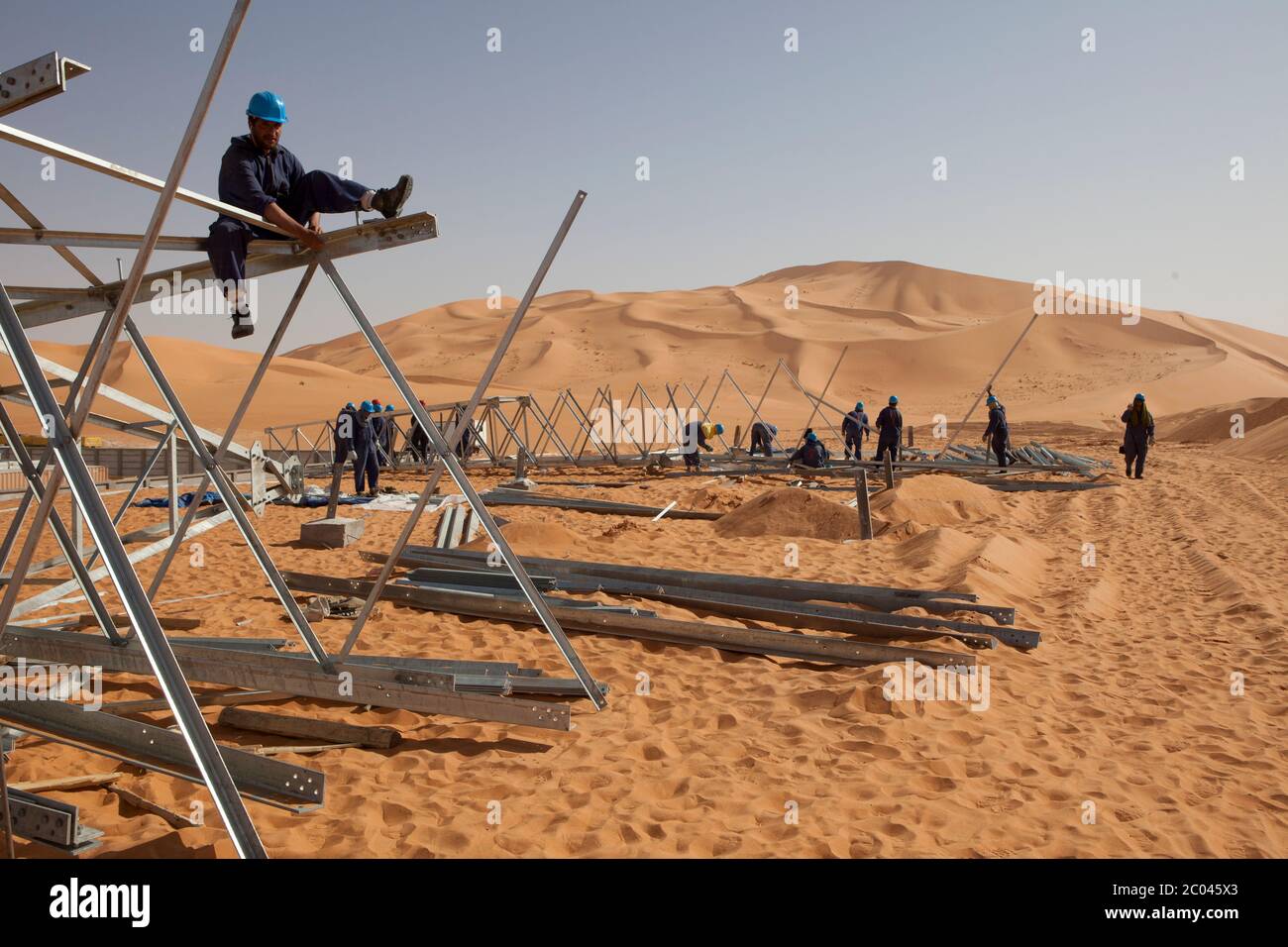 Workers assemble electricity pylons to carry power to a new large oil ...