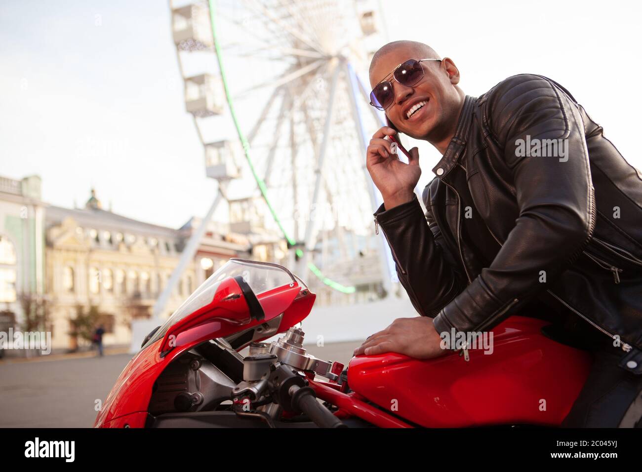 Happ handsome young man laughing, talking on the phone, sitting on a ...