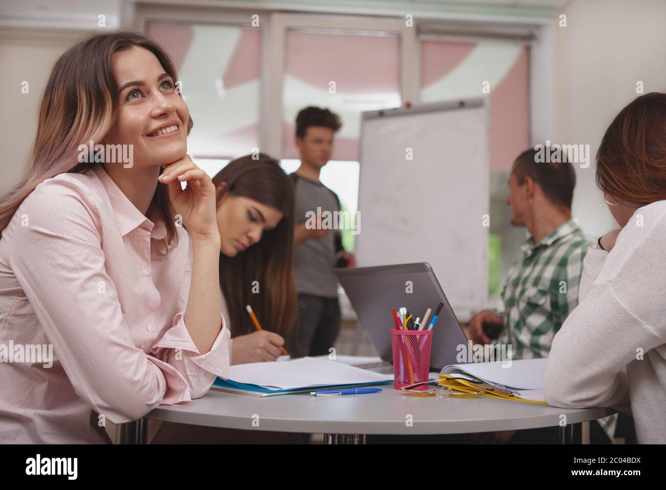 Beautiful happy young female student looking away dreamily, her ...