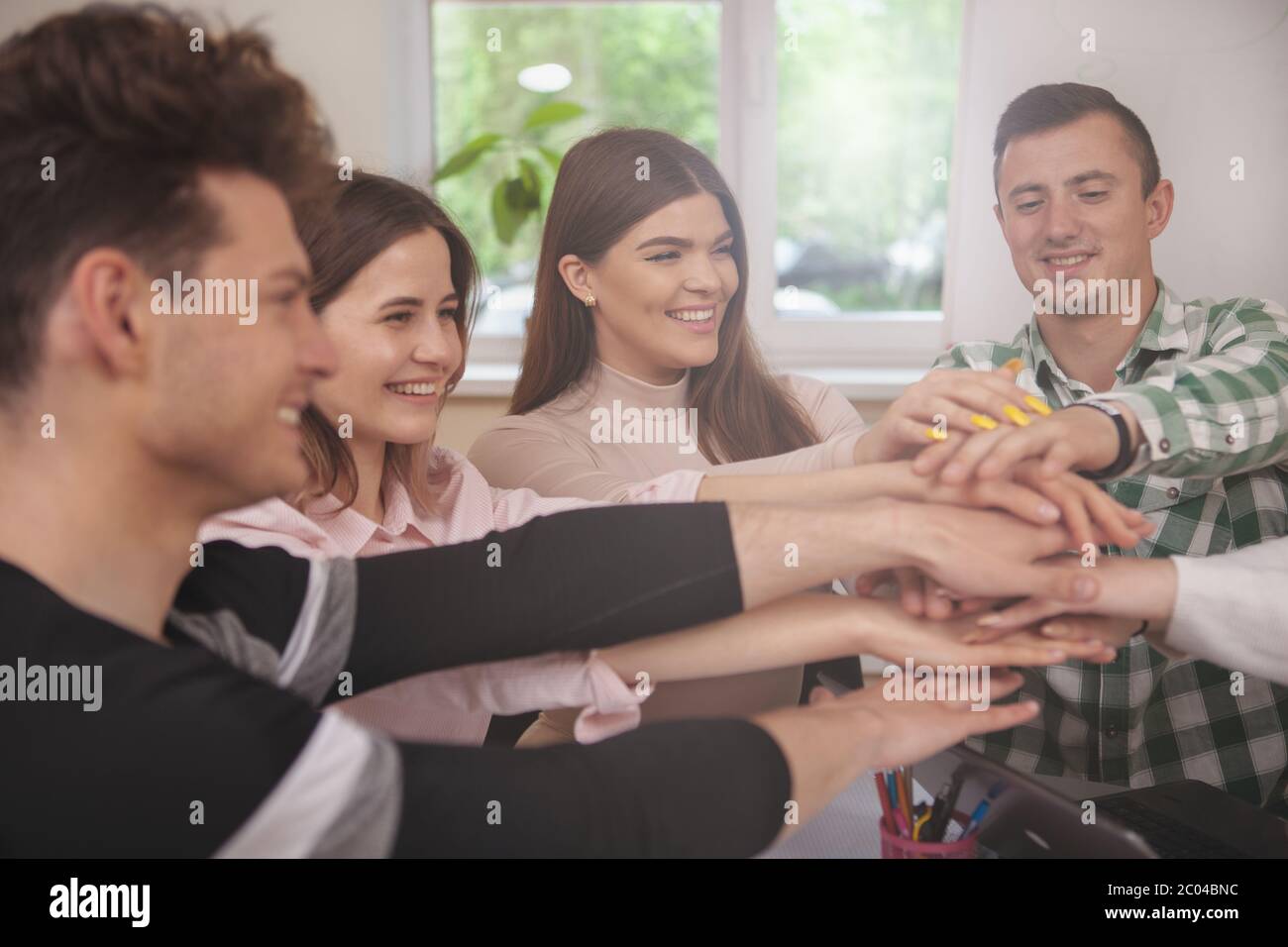 Unity, achievement, joining concept. Cropped shot of a group of college ...