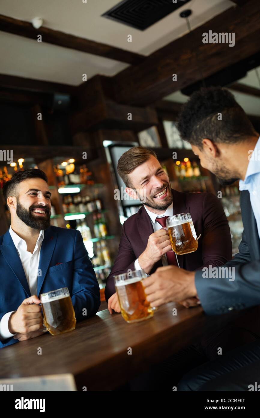 Young businessmen are drinking beer, talking and smiling while resting ...