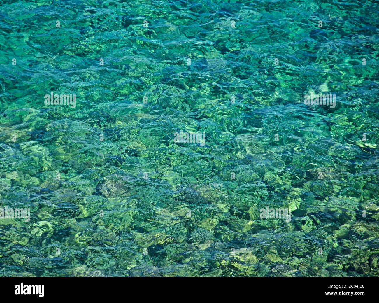 Turquoise colored rocks visible through clean and transparent sea water ...