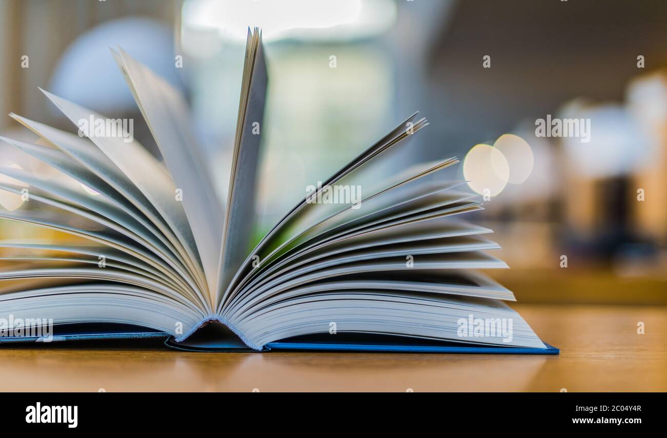 Open book lying on the table in the public library Stock Photo - Alamy