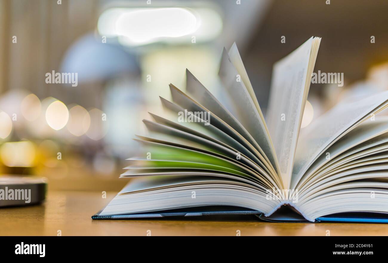 Open book lying on the table in the public library Stock Photo - Alamy