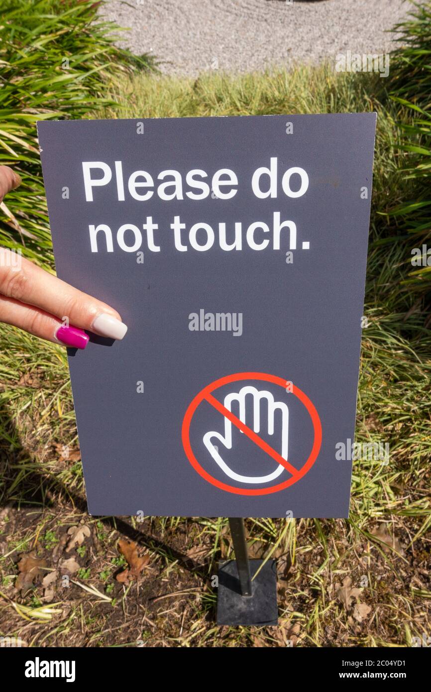 Woman touching a "Please do not touch" sign, in the Royal Botanic ...